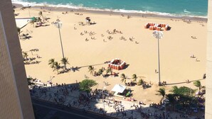 Uma praia com pessoas, palmeiras e uma vista desobstruída do oceano.