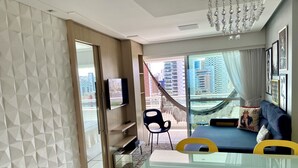 Uma sala de estar moderna com sofá, TV e vista para a cidade.