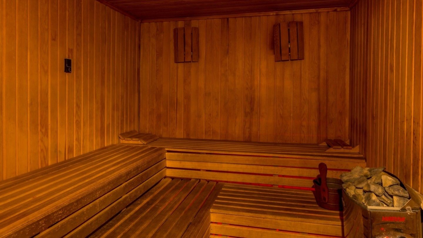Uma sauna de madeira com bancos e um balde de pedras.