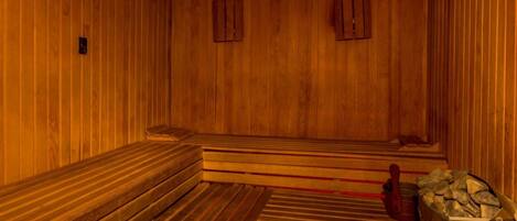 Uma sauna de madeira com bancos e um balde de pedras.