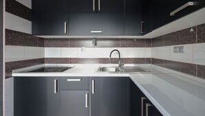 Uma cozinha moderna com armários escuros, bancadas brancas e azulejos de parede estampados.