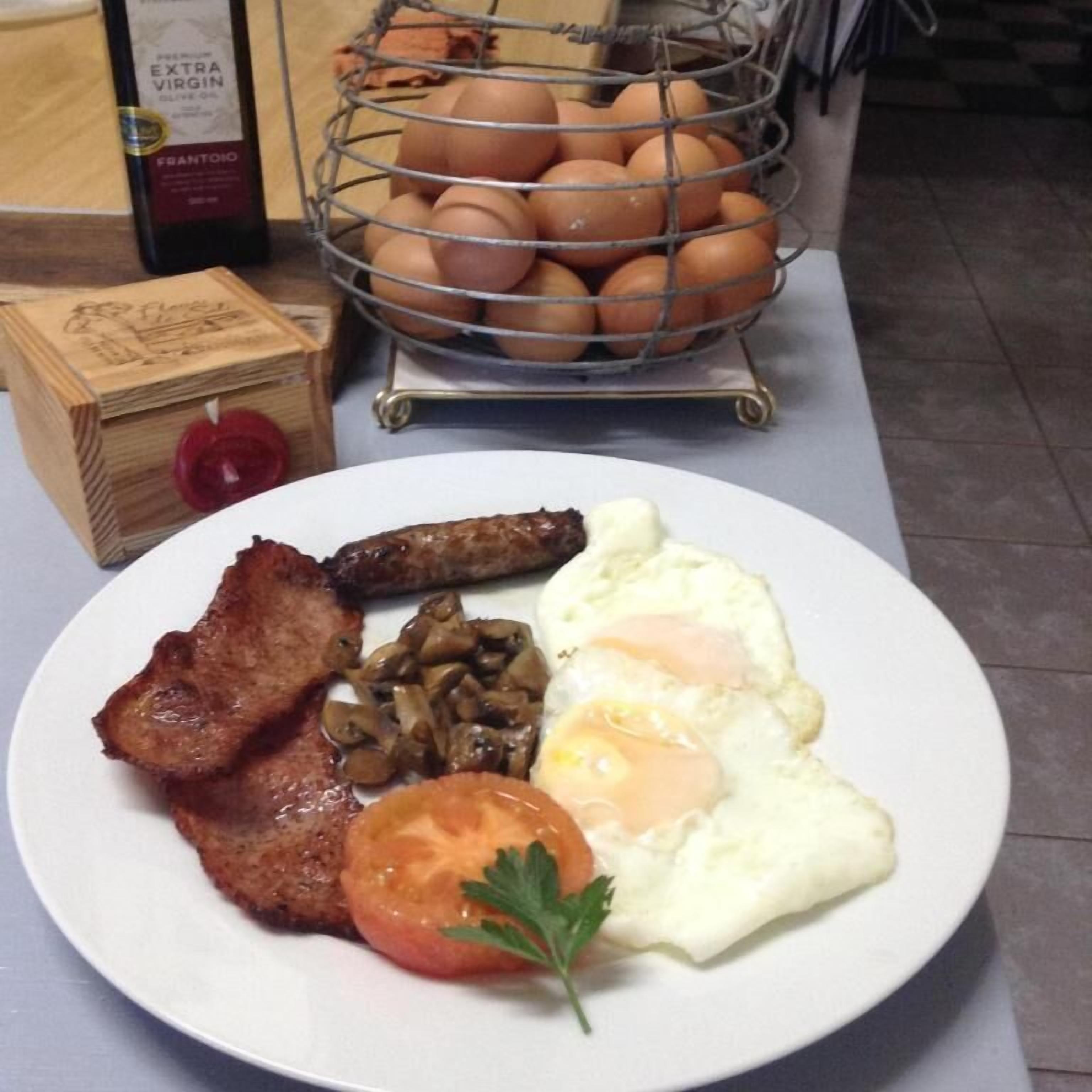 Um prato de comida de café da manhã com ovos, bacon, cogumelos e tomate.