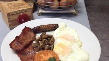 Um prato de comida de café da manhã com ovos, bacon, cogumelos e tomate.