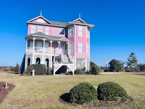Uma casa grande e cor-de-rosa, com vários andares, varanda e varanda frontal.