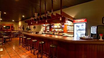 Uma área de bar com banquetas, balcão e frigorífico.