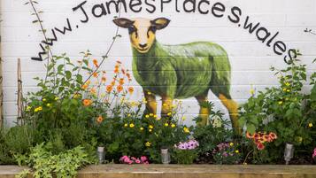 Um mural com uma ovelha e o texto "www.JamesPlacesWales" numa parede de tijolos brancos.