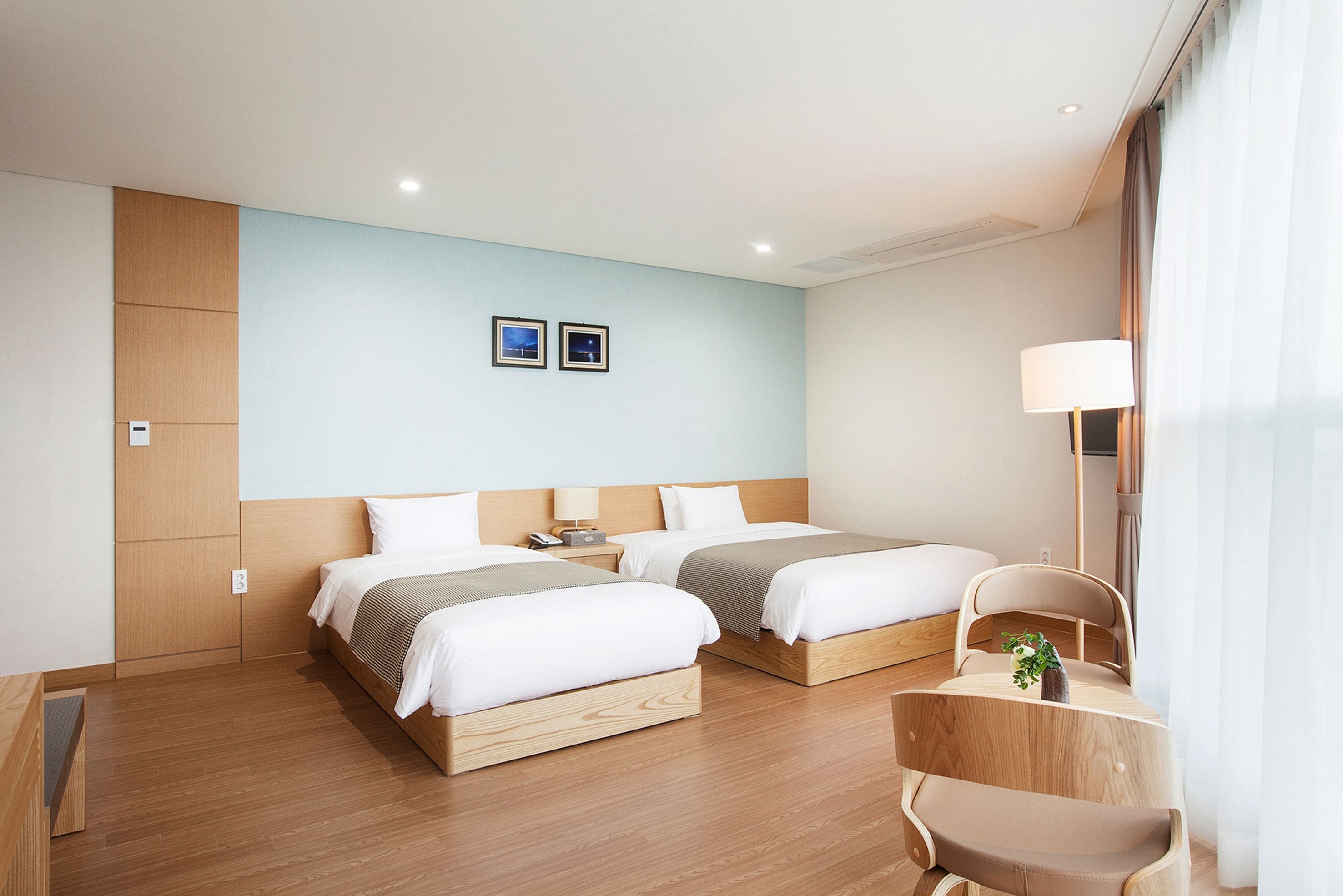 Quarto de hotel com duas camas, uma escrivaninha e uma cadeira.