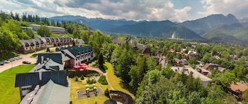 Um resort de montanha com edifícios no estilo chalé, um parquinho e vista para as montanhas ao redor.
