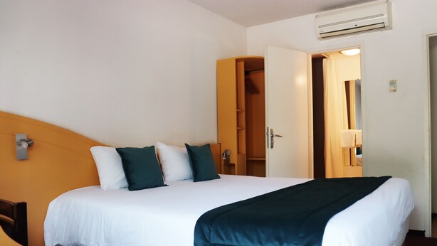 Quarto de hotel com uma cama grande, um guarda-roupa e uma escrivaninha.