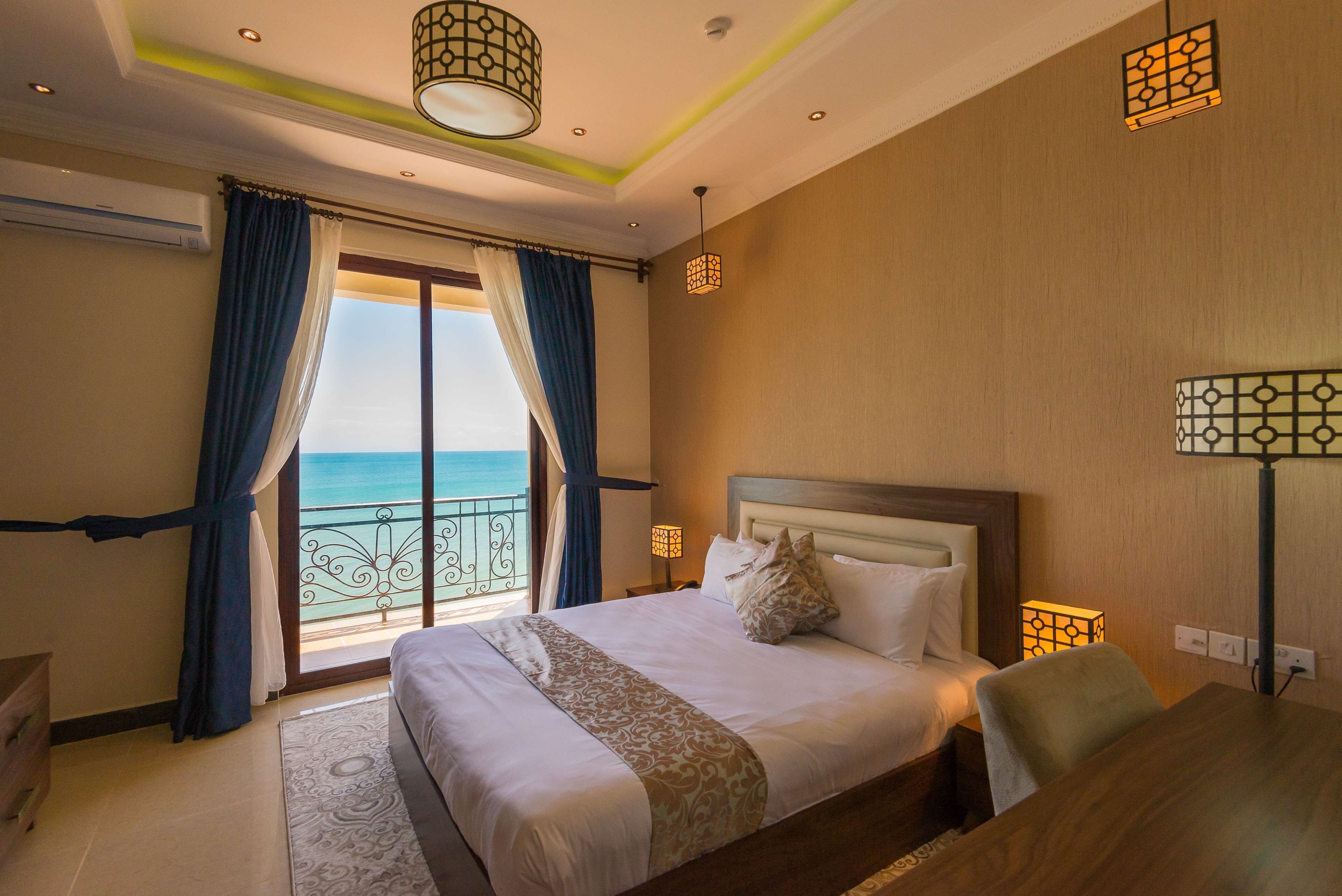 Quarto de hotel com uma cama grande, uma escrivaninha e vista para o oceano.