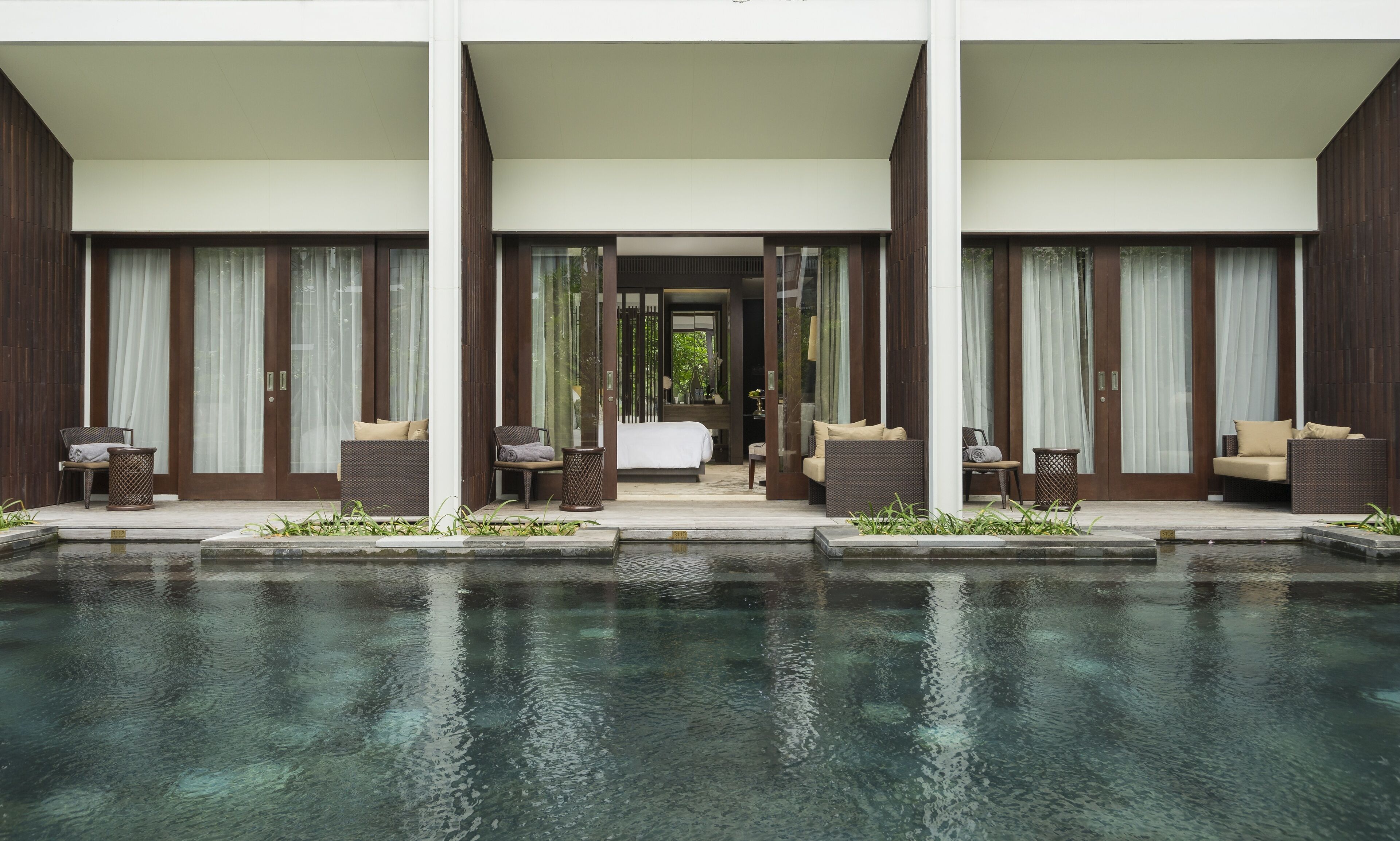 Um hotel moderno com piscina, área de estar externa e vista do interior.