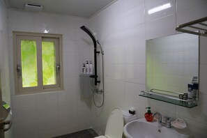 Casa de banho com chuveiro, sanita, lavatório e janela com vidro jateado.