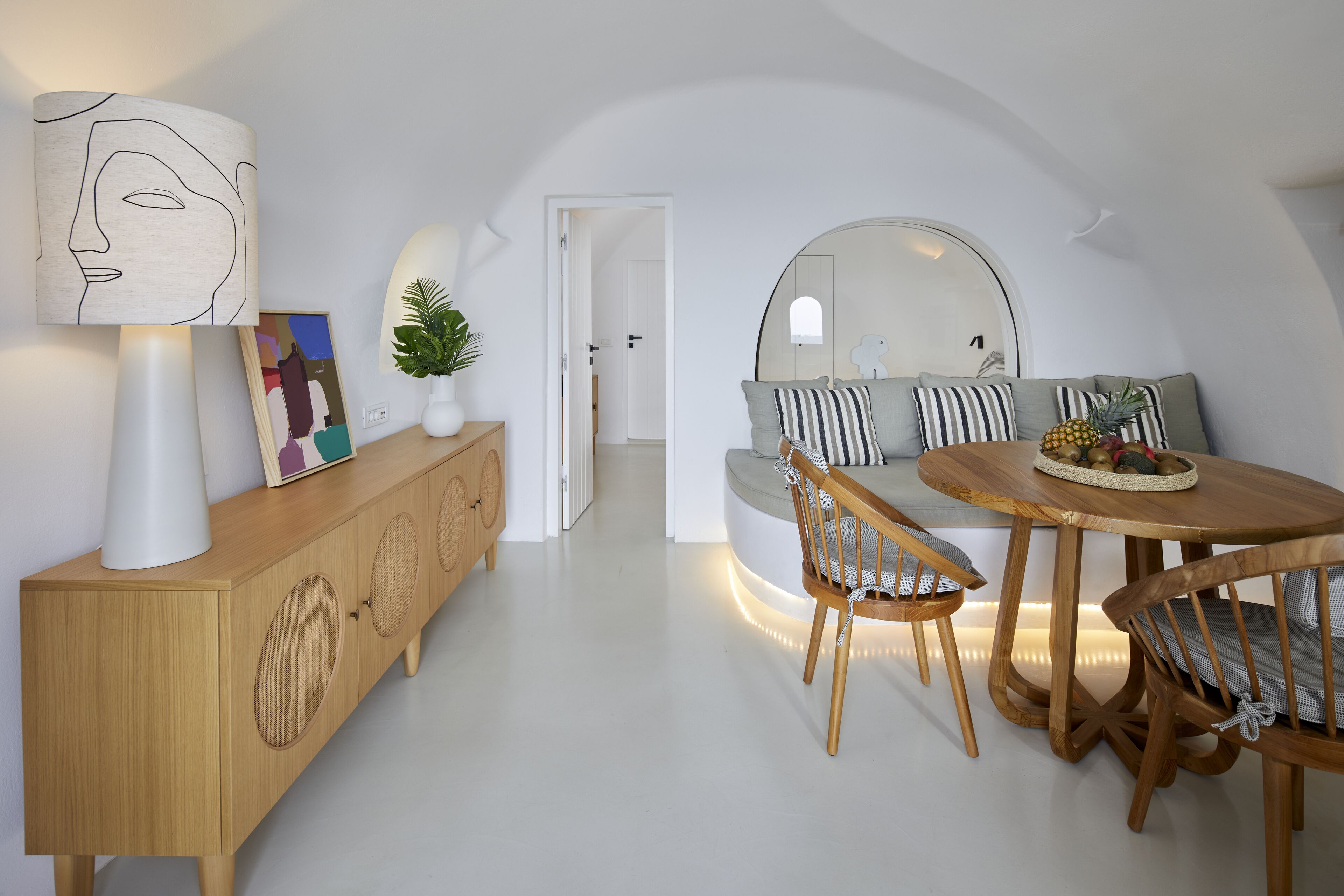 Uma sala de estar moderna com uma mesa de jantar de madeira, um sofá com almofadas listradas e um espelho grande.