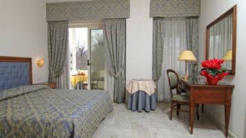 Quarto de hotel com cama, escrivaninha, cadeira, mesa pequena e espelho.