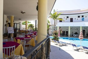 Um pátio de hotel com área de estar externa, piscina e vista do edifício.
