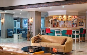 Um saguão de hotel com área de bar, disposição de assentos e lareira.