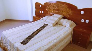 Uma cama bem arrumada com colcha estampada e almofada decorativa.