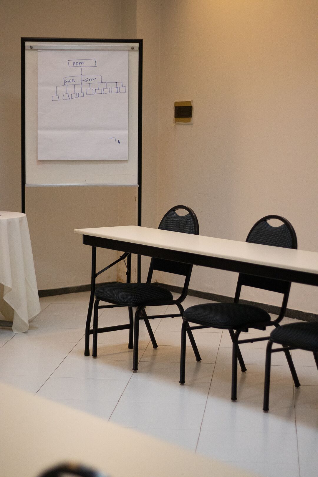 Uma sala de conferências com um quadro branco, uma mesa comprida e quatro cadeiras.
