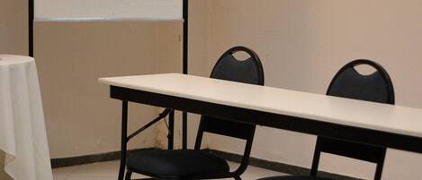 Uma sala de conferências com um quadro branco, uma mesa comprida e quatro cadeiras.