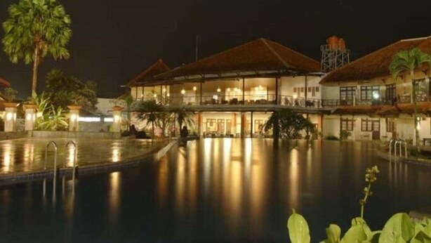 Um hotel com piscina, vários quartos de hóspedes e área externa bem iluminada.