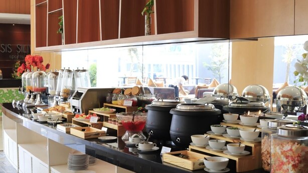 Buffet com diversos alimentos e bebidas, incluindo tigelas, pratos e recipientes.