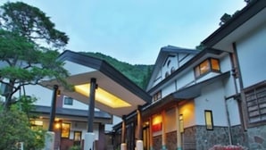 Um edifício moderno com entrada coberta, paredes de pedra e um jardim ajardinado.