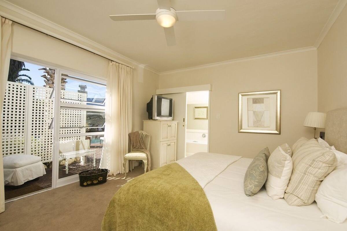 Quarto com cama, televisão, escrivaninha e janela com vista para o exterior.