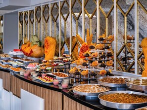 Buffet com diversos alimentos e uma parede dourada decorativa.
