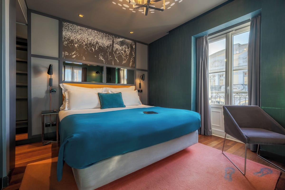 Quarto de hotel moderno com uma cama grande, uma escrivaninha e uma cadeira.