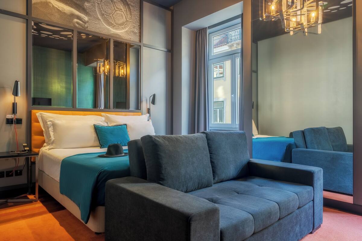 Quarto de hotel moderno com uma cama grande, um sofá e uma escrivaninha.