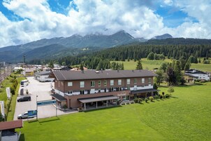 Um hotel com telhado plano, várias janelas e uma área externa coberta.