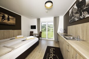 Quarto de hotel com cama, escrivaninha, pia e vista para o exterior.