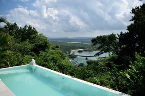 Piscina com vista para um rio e uma ponte ao fundo.