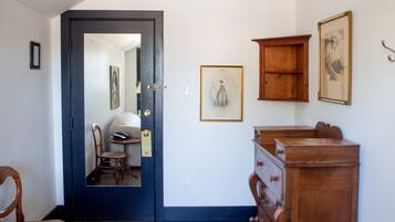 Um quarto com uma porta azul escura, um aparador de madeira e obras de arte emolduradas na parede.