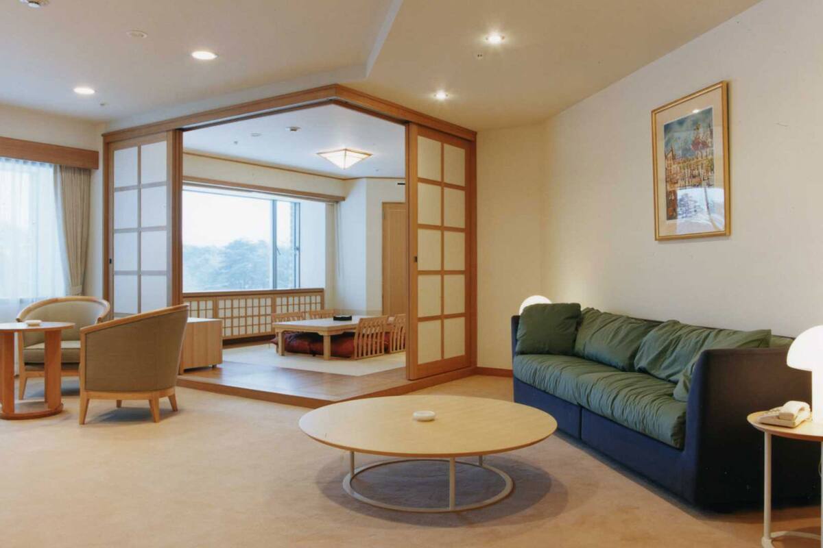 Uma sala de estar moderna com um sofá, uma mesa de centro redonda e um espaço de jantar com cadeiras e uma mesa.
