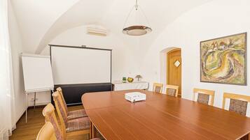 Uma sala de conferências com uma mesa comprida, cadeiras, um projetor, um quadro branco e um quadro na parede.