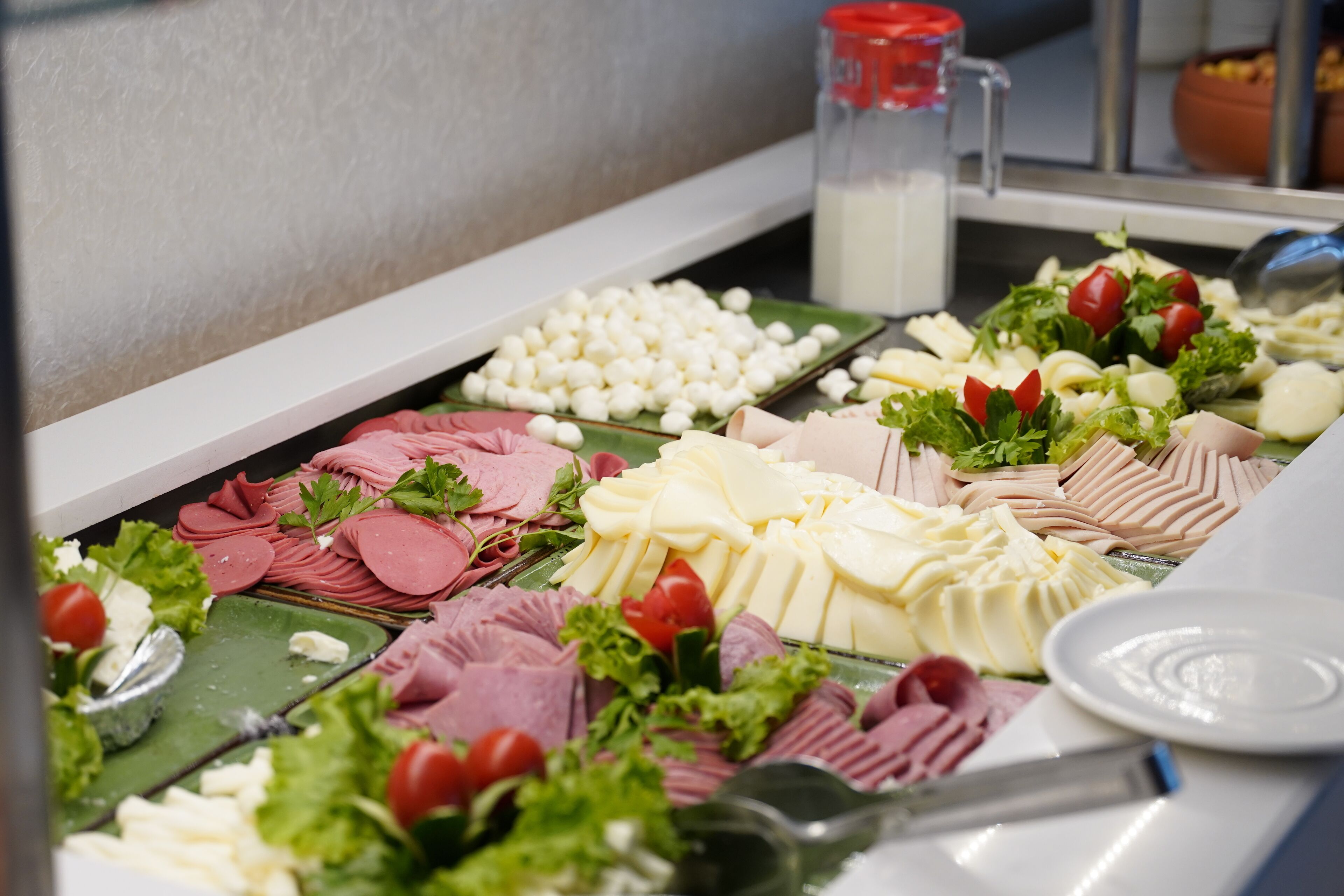 Buffet com diversos queijos, carnes e acompanhamentos.