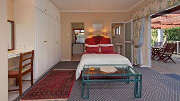 Quarto com cama, escrivaninha, cadeira, mesa de centro de vidro e tapete estampado.