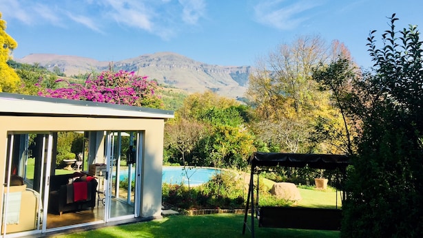 Uma casa moderna com porta de vidro que dá para um pátio, uma piscina e vista para montanhas.