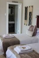 Quarto de hotel com duas camas, banheiro visível através de uma porta aberta e arte decorativa nas paredes.