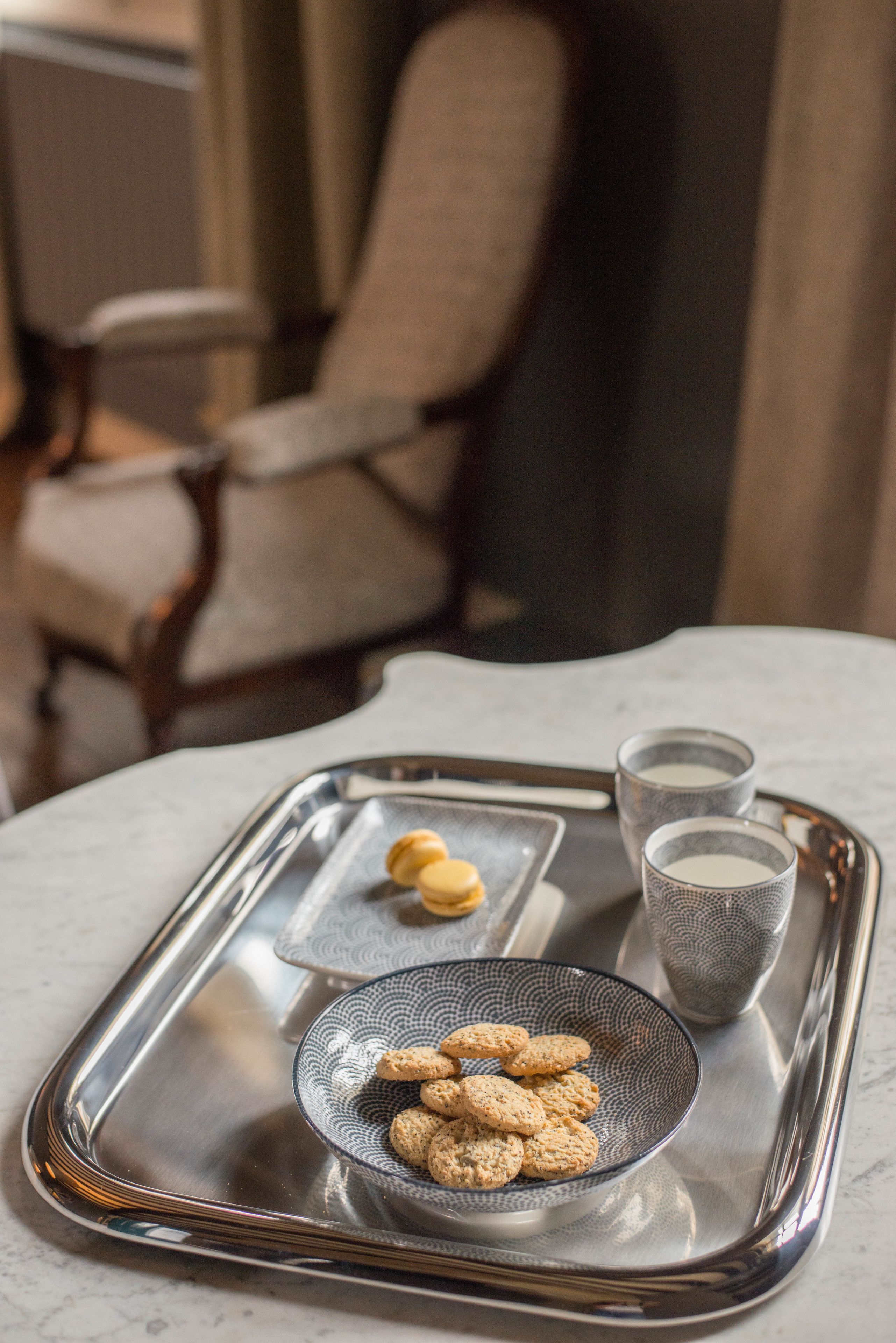 Uma bandeja com biscoitos e duas taças de leite sobre uma mesa de mármore.