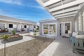 Uma área externa moderna com um terraço, assentos e um pequeno jardim.