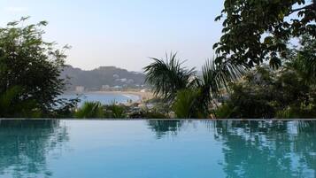 Visão clara de uma piscina com praia e colinas ao fundo.