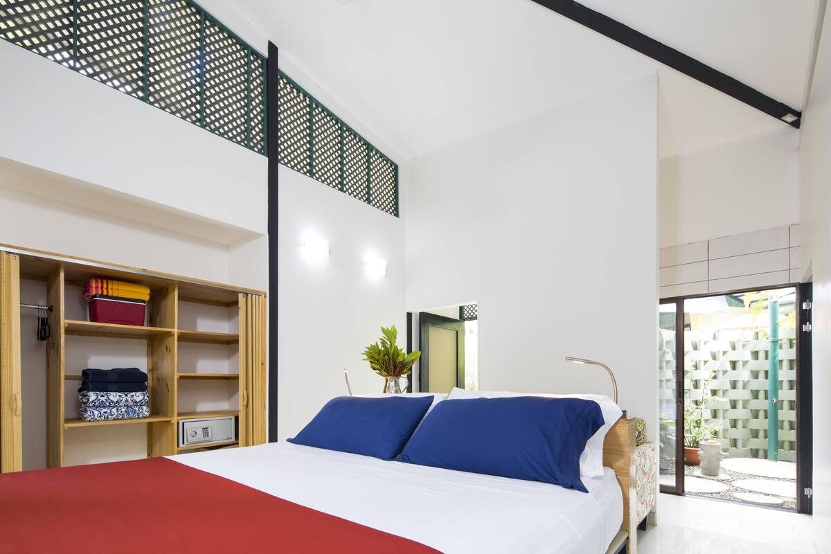 Quarto moderno com cama, guarda-roupa de madeira e varanda pequena com vista.