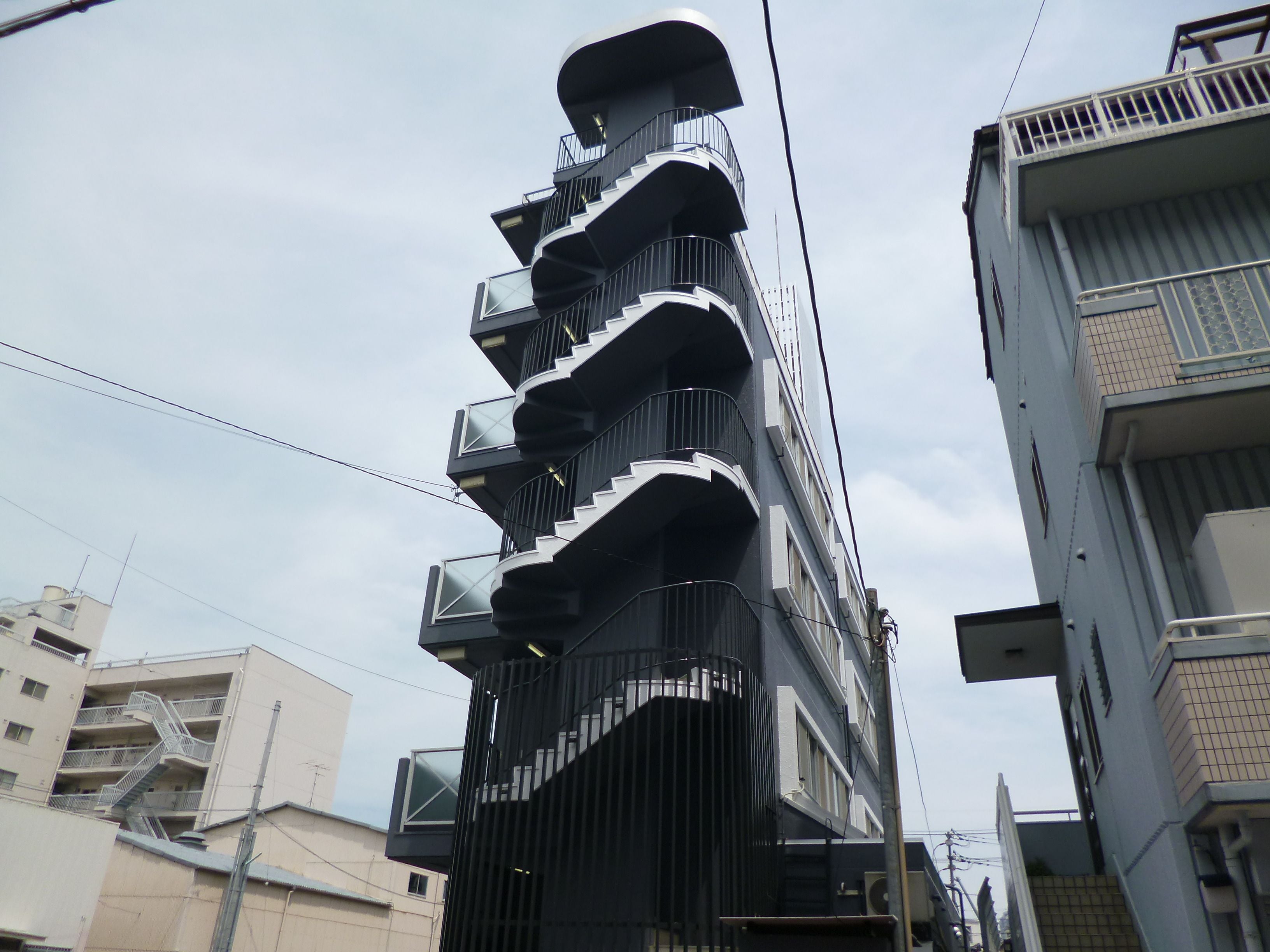 Um edifício moderno com design arquitetônico único, com várias varandas e uma série de escadarias.