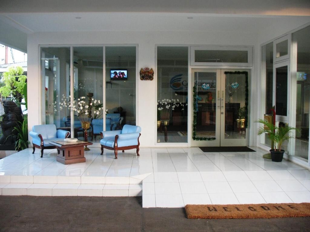 Um saguão de hotel moderno, com balcão de recepção, área de estar e portas de vidro que dão para o interior.