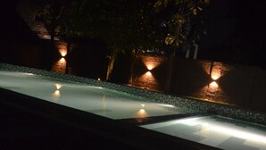 Piscina com paredes revestidas em azulejo e um muro de tijolos ao fundo.