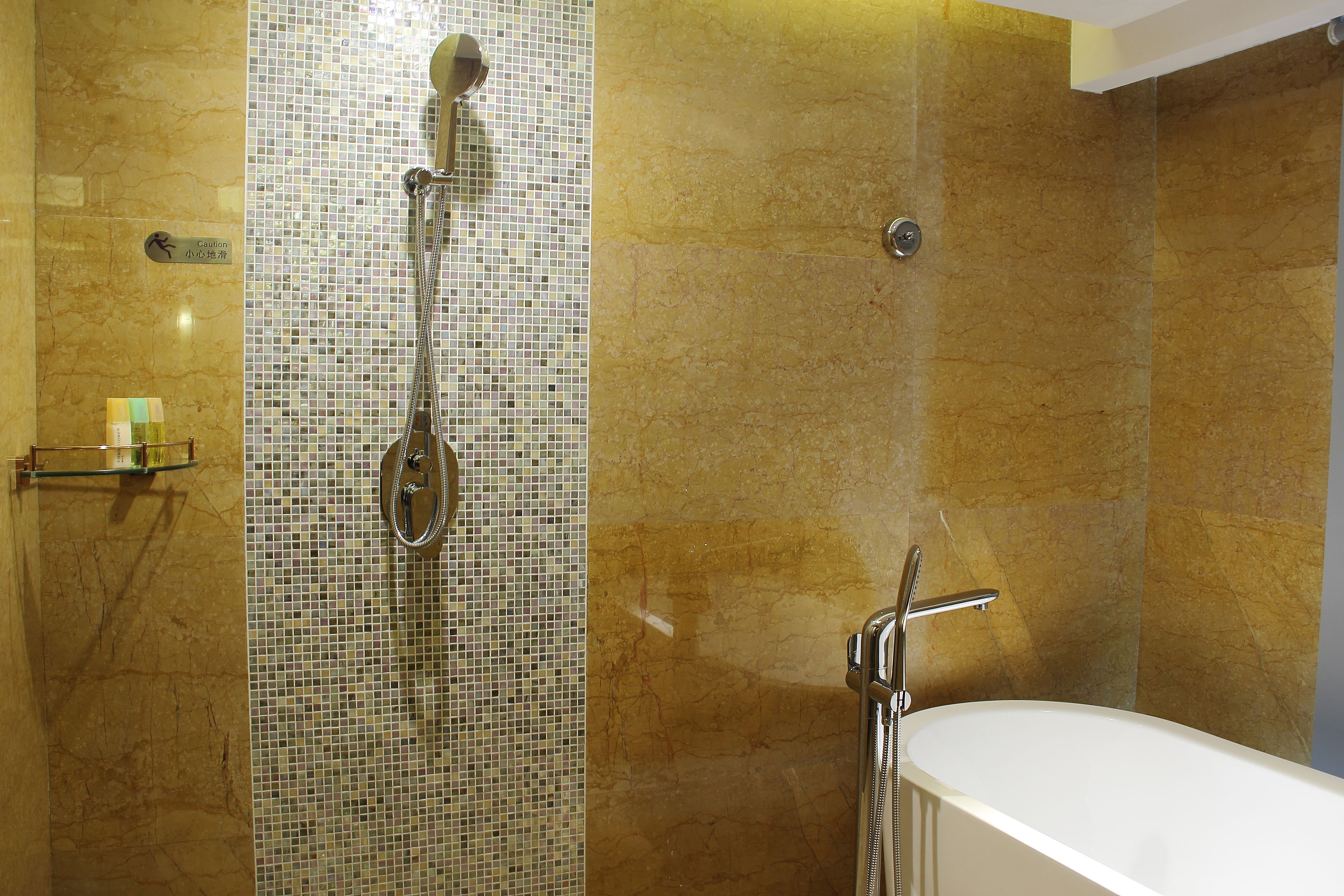 Casa de banho com chuveiro, banheira e parede revestida a azulejos.