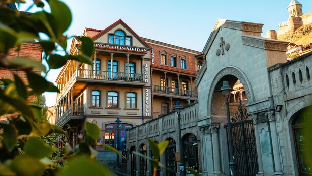 Um edifício histórico com vários andares, varandas e uma entrada em arco imponente.