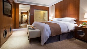 Quarto de hotel com cama grande, mesa de cabeceira, espelho e guarda-roupa.